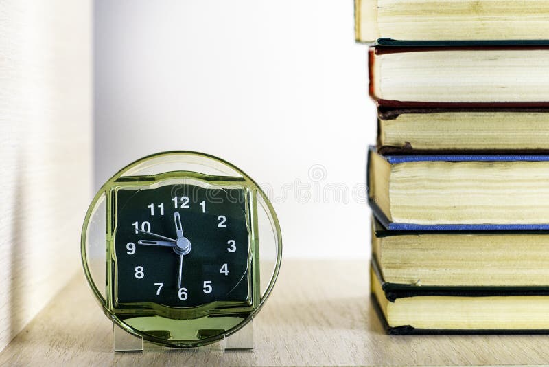 The Clock is on the Shelf Next To a Stack of Books Stock Photo - Image ...