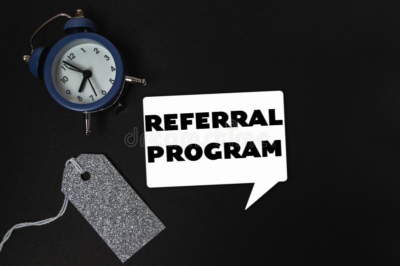 A Clock is on a Table with a Tag that Says Referral Program Stock Photo ...