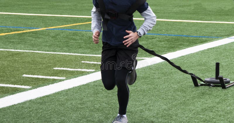 Close Up of Athlete Pulling a Sled Carrying Extra Weight on a Turf ...