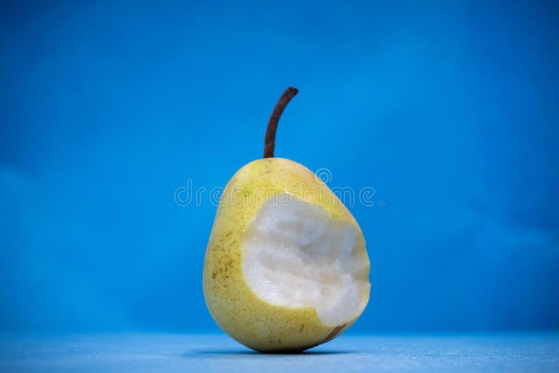 Close Up of a Bitten Pear is Standing and the Background is Blue Stock ...