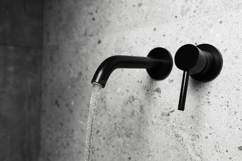 Close Up Of Black Matte Wall Mounted Basin Tap With Flowing Water
