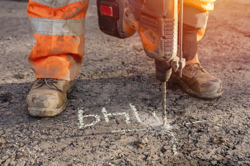 Builder Using a Cordless Hammer Drill To Drill Holes in the Road at the ...