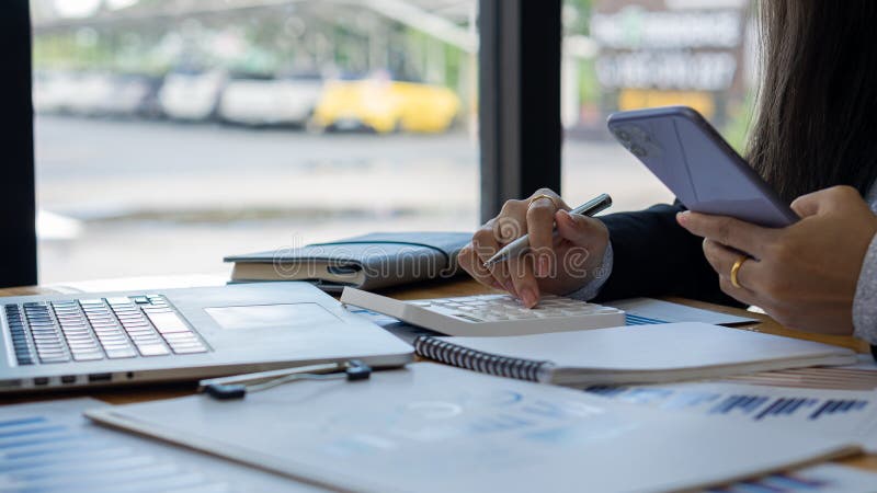 Close-up Business People Using a Calculator To Write Notes with ...