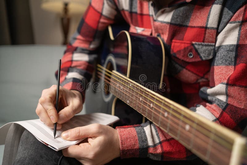 Close-up of Composer Writing and Examining Sheets with Notes for Guitar ...