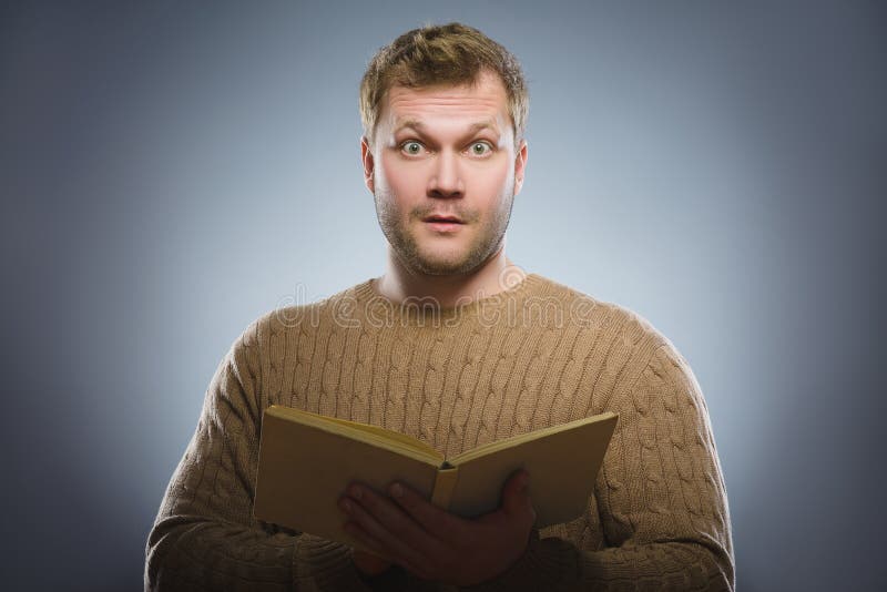 Close-up Of Confused Man Reading Book Against Gray Background Stock ...