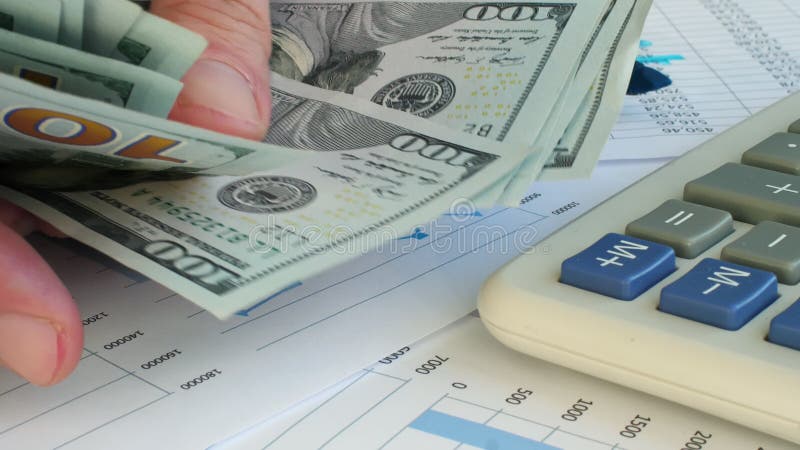 Counting Cash and Using a Calculator at a Desk in a Modern Office ...