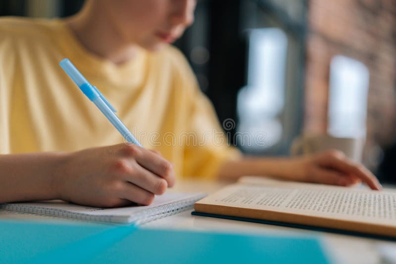 Side View of Focused Schoolboy Studying at Home Doing Homework Sitting at Table Under Light of ...