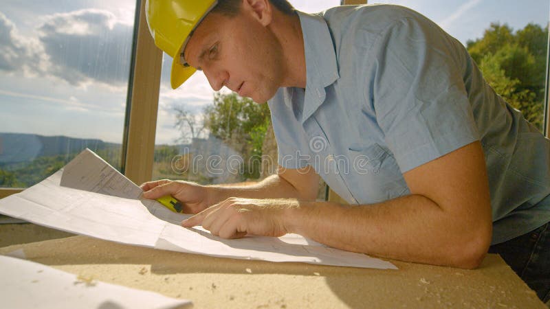 CLOSE UP: Diligent Contractor Looks at the Blueprints Lying on His ...