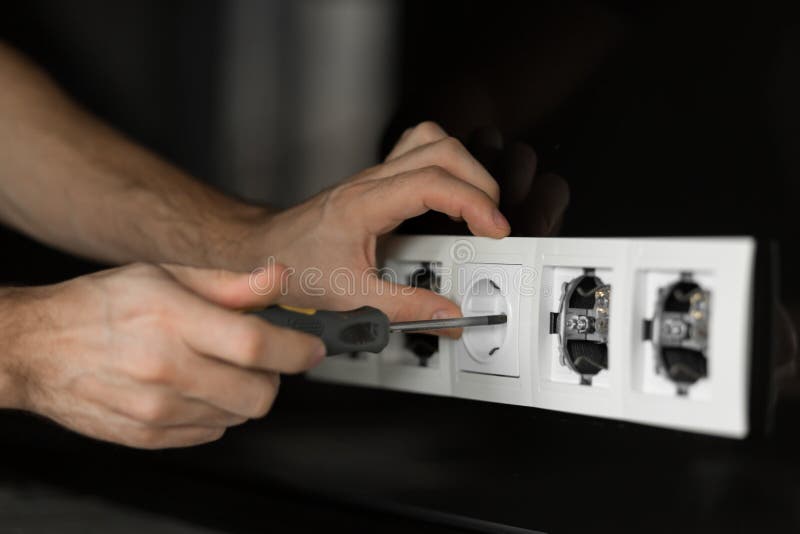 Close-up of an Electrician`s Hand with a Screwdriver Disassembling a ...