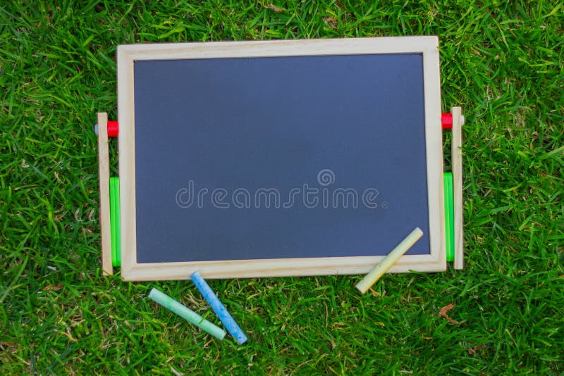 Close Up Empty Black Chalkboard and Colors Chalks on Green Grass, , Top ...