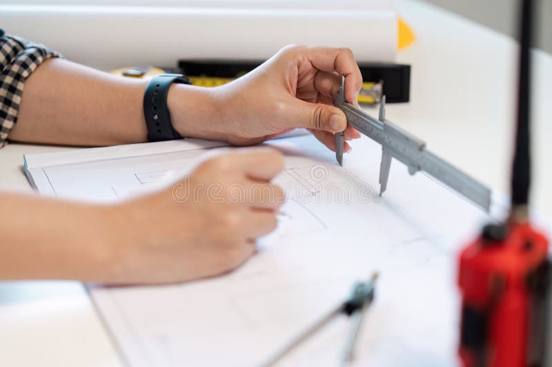 Engineer Measuring Blueprint with Caliper in Modern Office Setting for ...