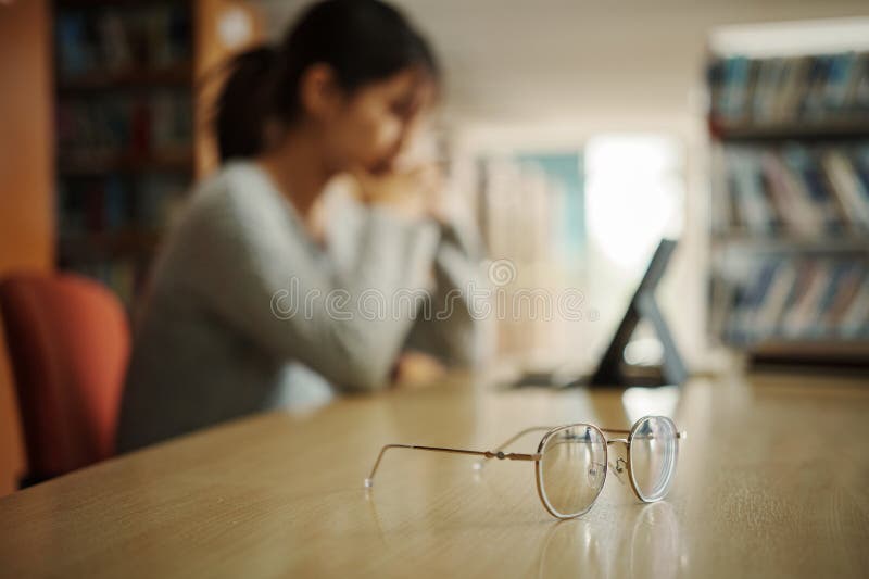 Close Up of Eyeglasses on Table with Unhappy Girl Student Using Tablet ...