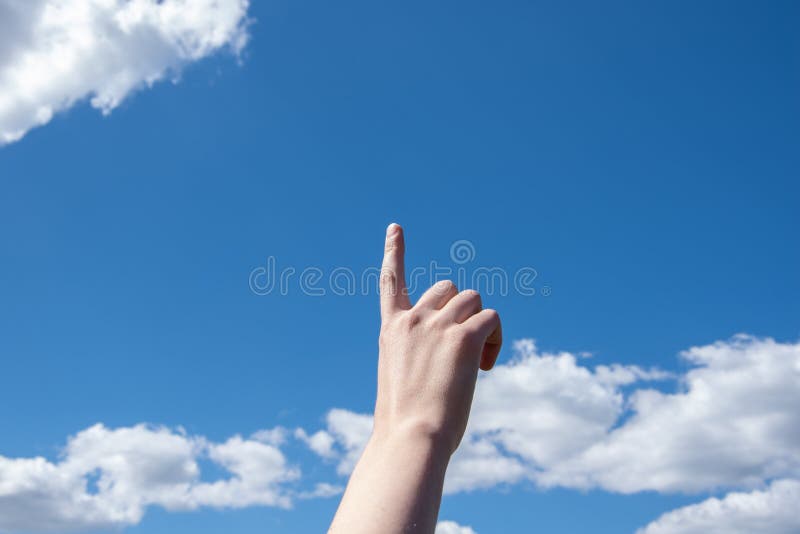 Close-up Female Hand with Index Finger Up on a Background of Blue Sky ...