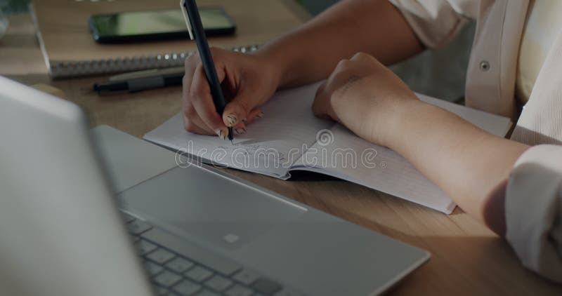Close-up of Female Hand Writing in Notebook and Using Laptop while ...