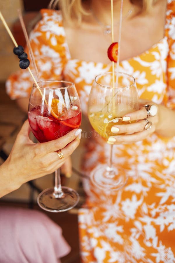 Close Up Of Female Hands Holding Glasses Of Acohol Cocktails With Fresh