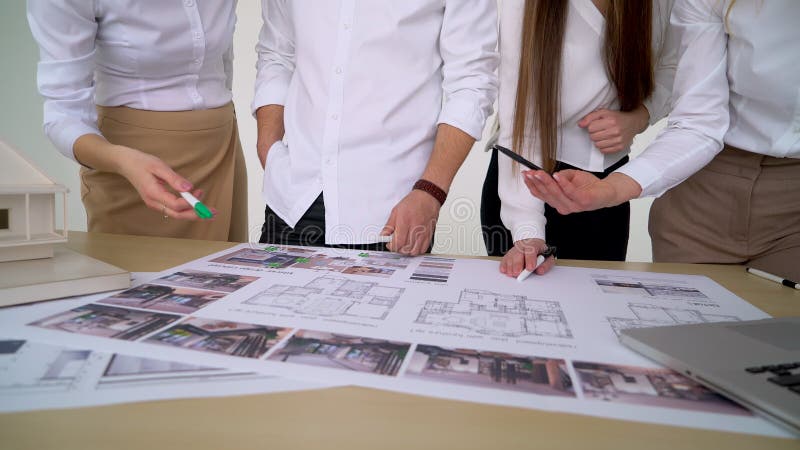 Close Up of Four Architects Discussing Plan Together at Desk with ...