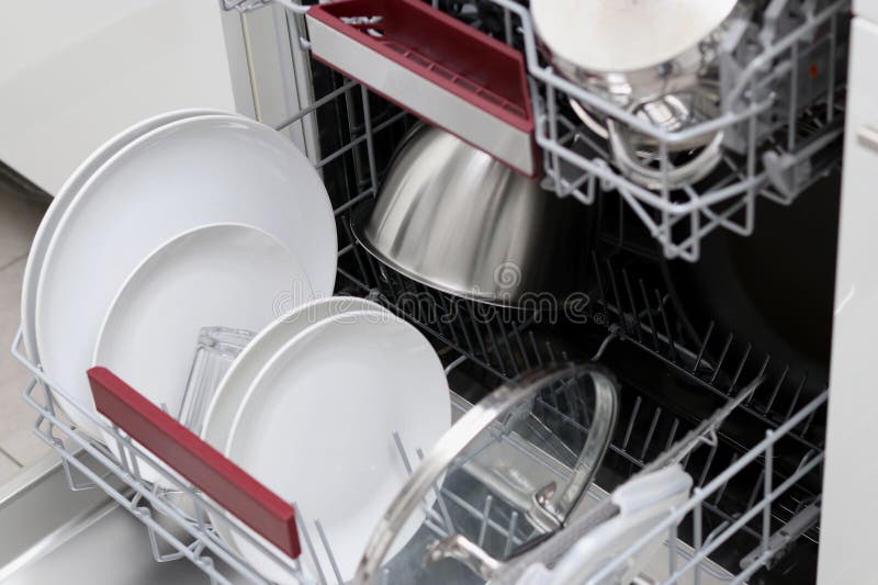 Close Up of a Full Dishwasher with Clean Plates, Lids, Glassware in the ...