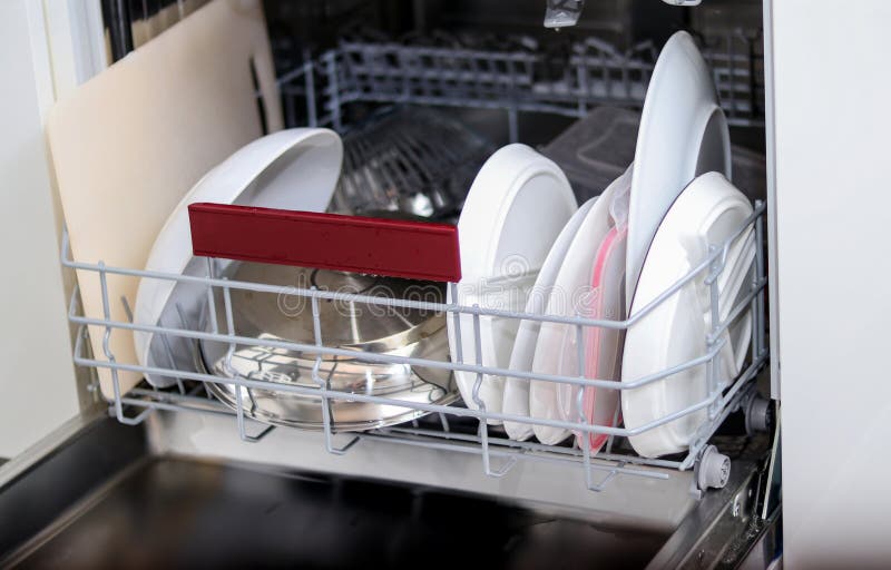 Close Up of a Full Dishwasher with Clean Plates, Lids, Glassware in the ...