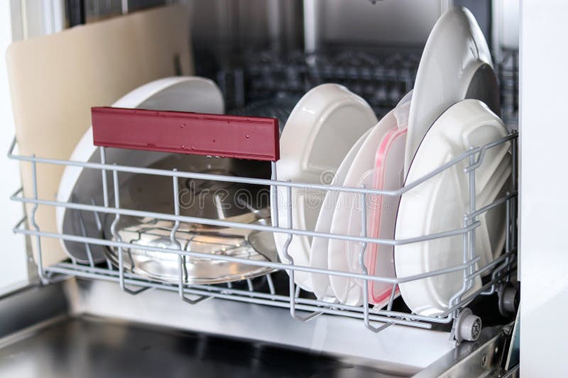 Close Up of a Full Dishwasher with Clean Plates, Lids, Glassware in the ...