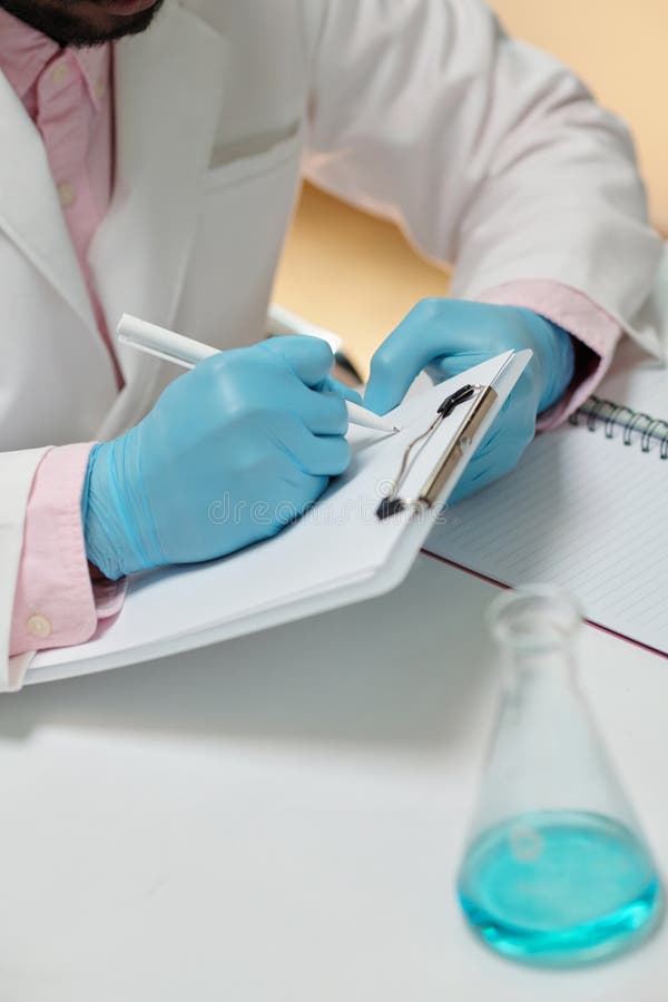 Close-up of Gloved Hands of Young Scientist Making Notes in Document ...