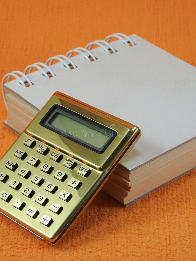 Close-up of a Golden Calculator and a Small Blank Notepad on an Orange ...