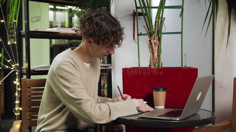 Close-up of a Guy Sitting in a Cafe with a Laptop at a Table, Drinking ...