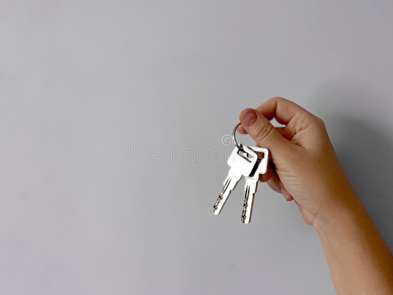 Close Up of Hand Holding Set of Silver Keys Against Plain Light Grey ...