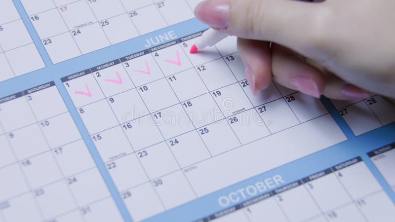 Close-up of a Hand Checking Off Dates on a Calendar Using a Pink Marker ...