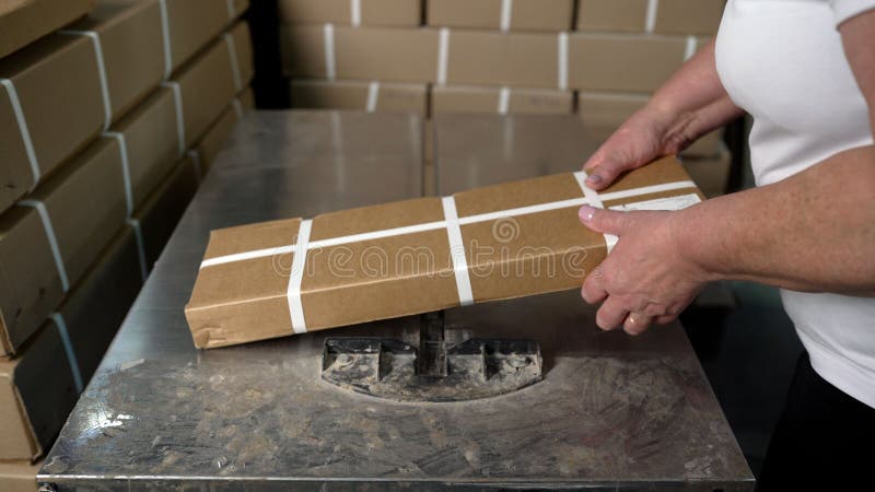Close-up of a Hand Packing a Cardboard Box with Tape in a Warehouse ...