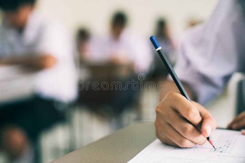 Close Up Hand of Student Reading and Writing Exam Answer Sheets ...