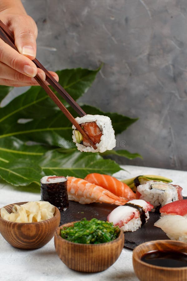 Close Up of Hand Taking Roll with Chopsticks from a Plate Stock Photo ...