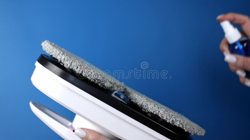Close-up of Hands on a Blue Background Shows a Robot Window Cleaner ...