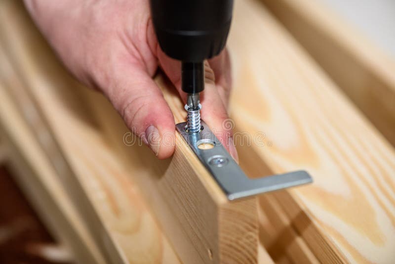Close Up On Hands With Cordless Screwdriver Assembling Furniture Stock