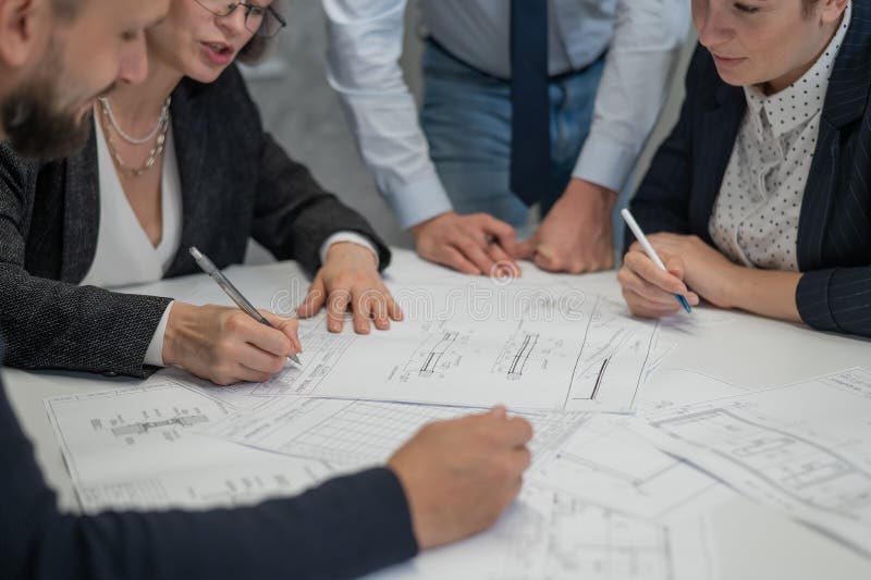 Close-up of the Hands of Four Colleagues with Blueprints on the Table ...