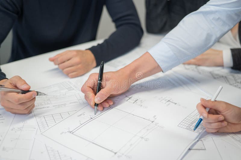 Close-up of the Hands of Four Colleagues with Blueprints on the Table ...