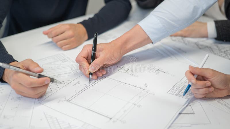 Close-up of the Hands of Four Colleagues with Blueprints on the Table ...