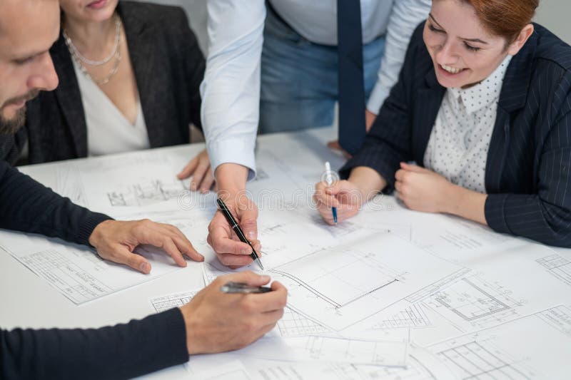 Close-up of the Hands of Four Colleagues with Blueprints on the Table ...