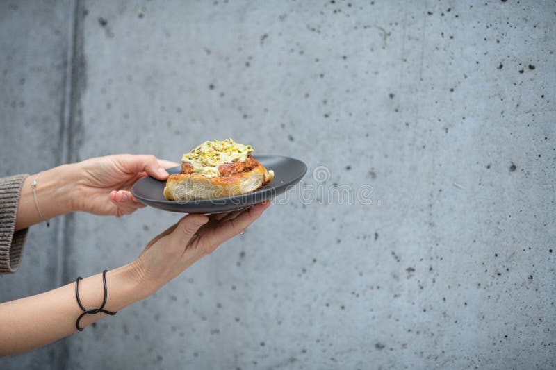 Close Up of Hands Holding Plate with Cinnamon Roll. Stock Image - Image ...