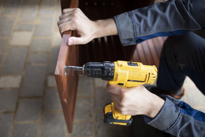 Close Up Hands Of Man Holding Yellow Cordless Screwdriver Machine And