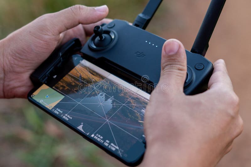 Close-up of Hands Operating a DJI Drone Controller with a Smartphone ...