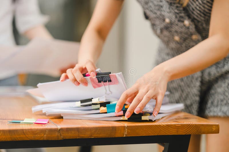 Close-up of Hands Organizing a Stack of Documents with Colorful Binder ...