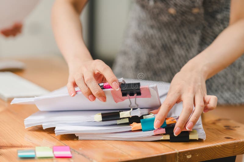 Close-up of Hands Organizing a Stack of Documents with Colorful Binder ...