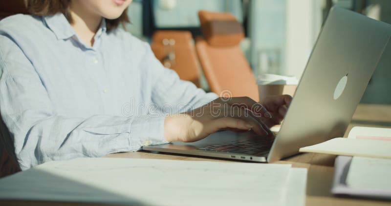 A Close-up of Hands Typing on a Laptop Keyboard with Charts, Documents ...