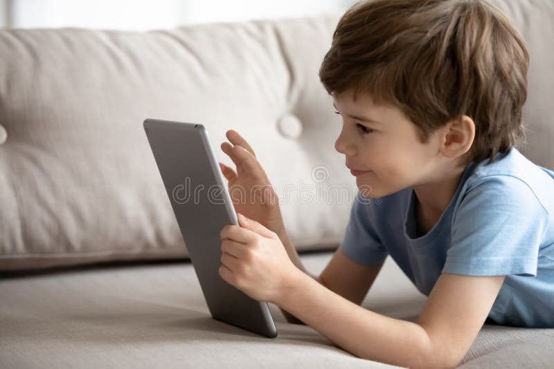 Close Up Little Boy Using Computer Tablet, Lying on Couch Stock Photo ...