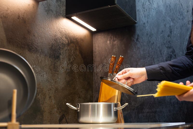 Close-up. a Man Cooks Spaghetti in the Kitchen. he Dips the Pasta into ...