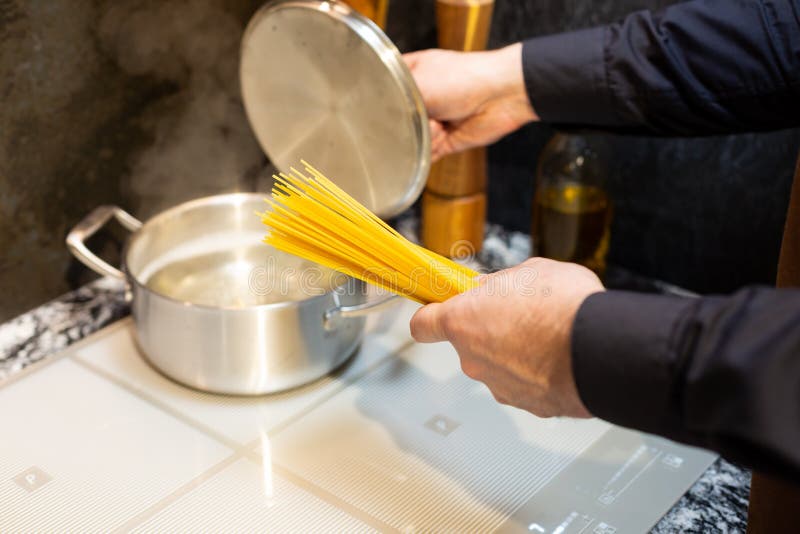 Close-up. a Man Cooks Spaghetti in the Kitchen. he Dips the Pasta into ...
