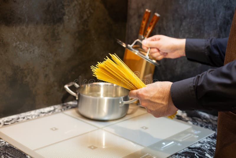 Close-up. a Man Cooks Spaghetti in the Kitchen. he Dips the Pasta into ...