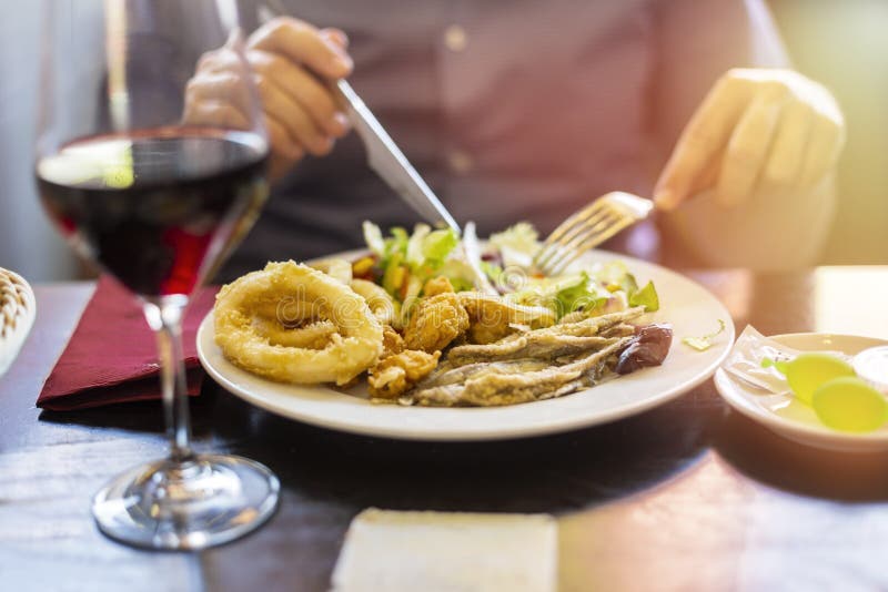 Close Up of a Man Eating Fried Fish at a Restaurant. Variety Fish Dish ...