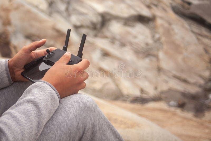 Close-up of Man Holding Drone Remote Controller while Sitting on Rock ...
