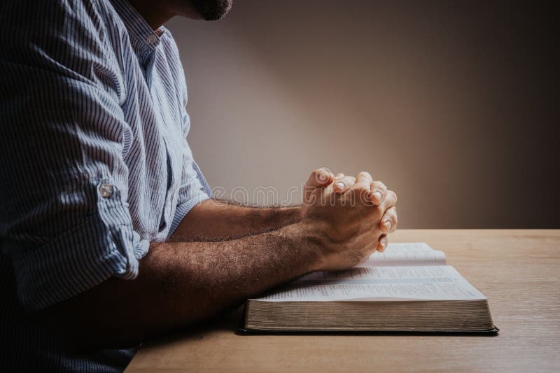 Man is Praying with His Hands Together Over the Open Bible, Side View ...